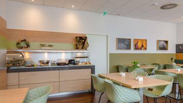 Uma área de refeições moderna com buffet, cadeiras verdes e teto de madeira.