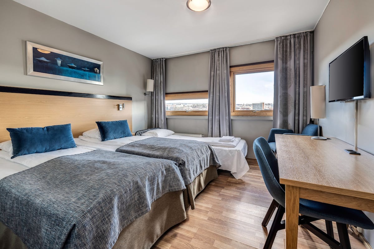 Quarto de hotel com duas camas, uma escrivaninha e uma televisão.