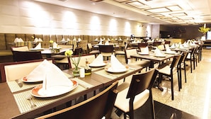 Um restaurante com várias mesas preparadas para refeições, incluindo guardanapos, talheres e centros de mesa.