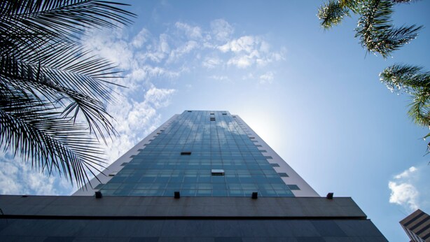 Um edifício alto com fachada de vidro e céu claro.