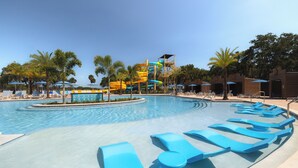 Piscina com cadeiras de descanso azuis e um tobogã.