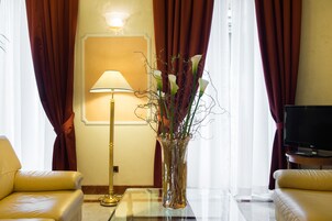 Um quarto com um sofá, uma mesa com um vaso, uma luminária e uma televisão.