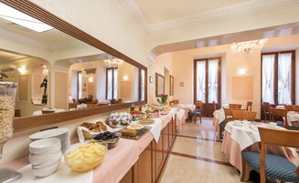 Espaço de refeições com serviço de buffet, incluindo diversos alimentos e uma mesa longa com cadeiras.