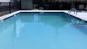 Piscina retangular com uma escada de metal em um dos lados.