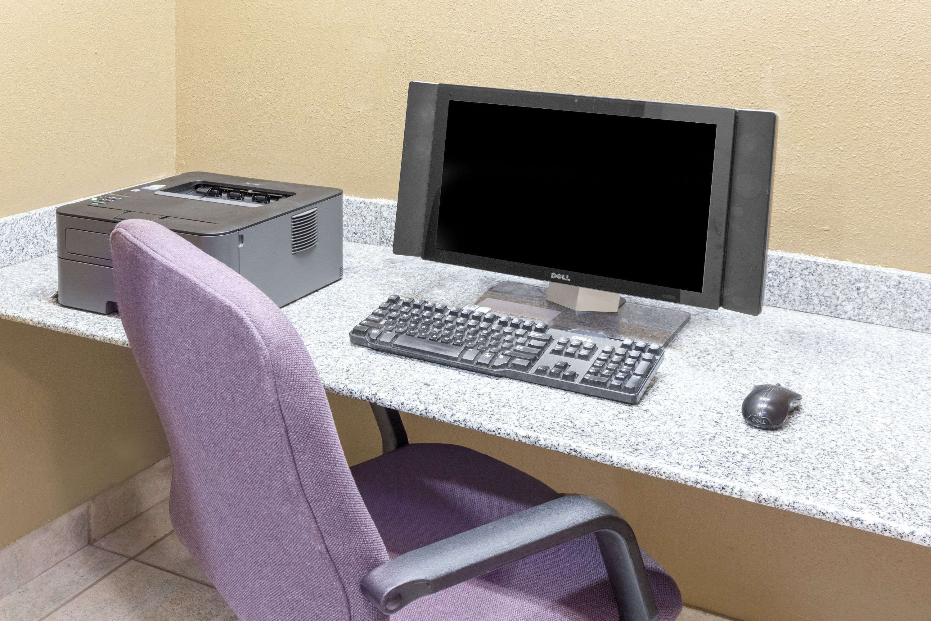 Uma área de trabalho com computador de mesa, teclado, rato e impressora.