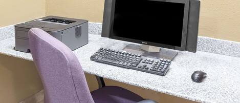 Uma área de trabalho com computador de mesa, teclado, rato e impressora.