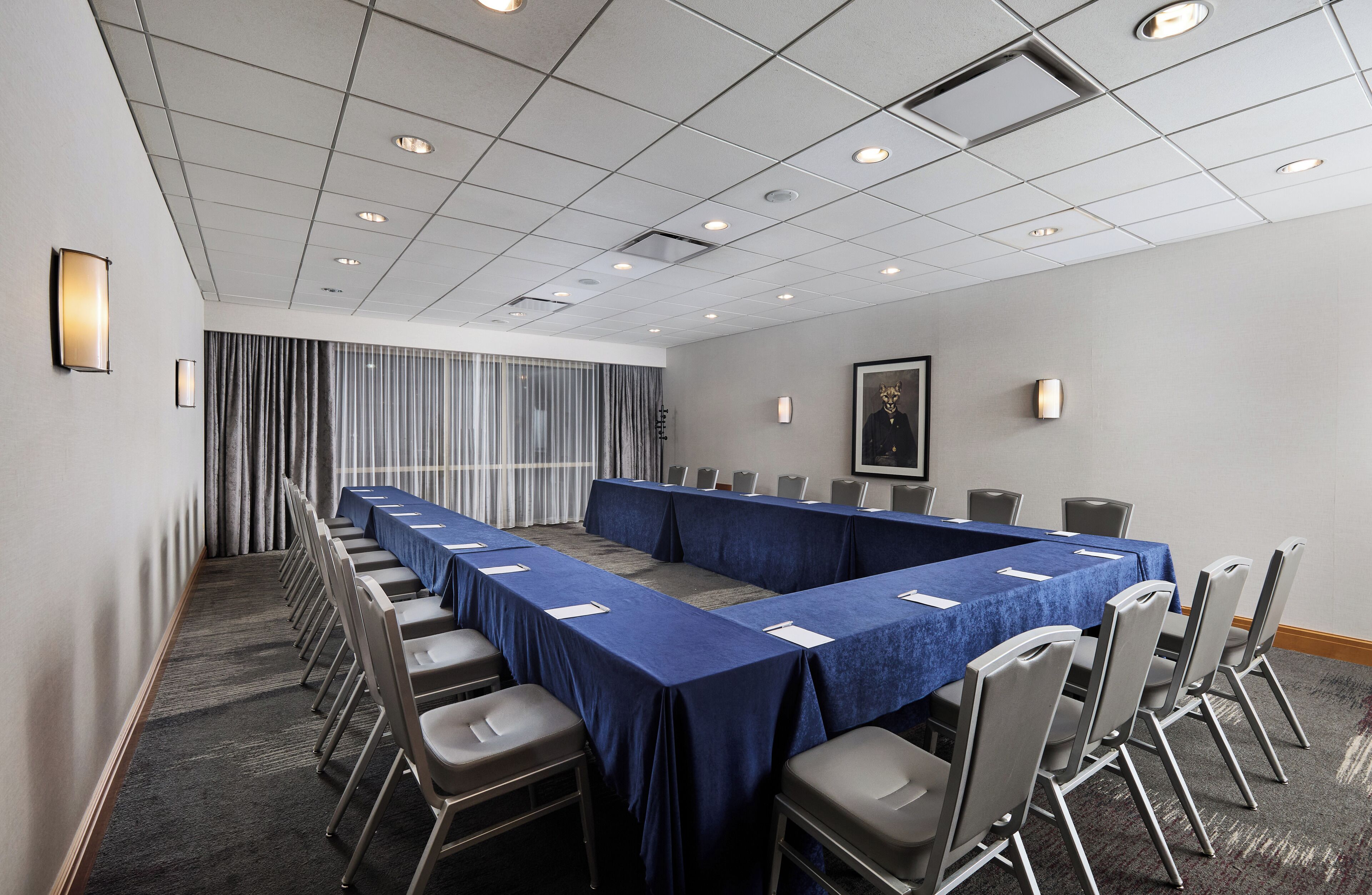 Sala de conferência com uma mesa comprida, cadeiras e um fundo de cortina.