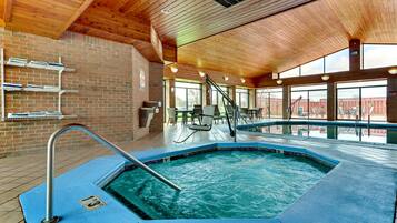 Uma área de piscina com teto de madeira, uma banheira de hidromassagem e um espaço de estar com cadeiras e mesas.