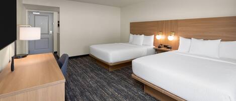 Quarto de hotel com duas camas, uma escrivaninha e uma cadeira.