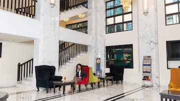 Um hall amplo com piso de mármore, uma escadaria e um candelabro.
