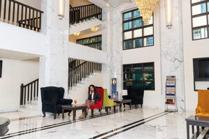Um hall amplo com piso de mármore, uma escadaria e um candelabro.