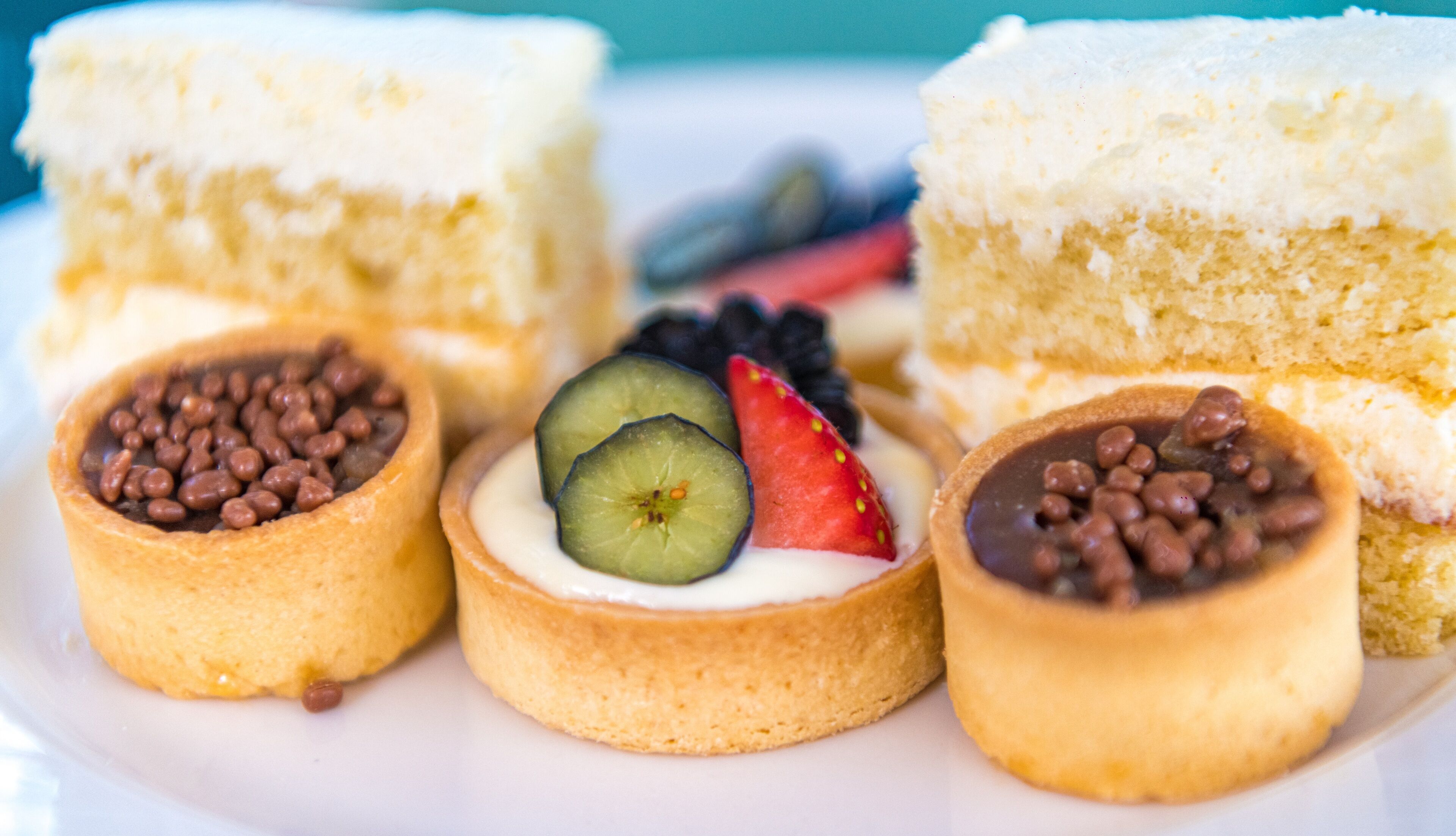 Um prato com três miniaturas de torta e duas fatias de bolo.