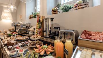 Buffet com diversas opções de comida, incluindo frutas, queijos e doces.