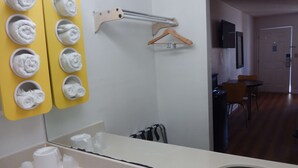 Casa de banho com um porta-toalhas amarelo, espelho, lavatório e um cabide de madeira.