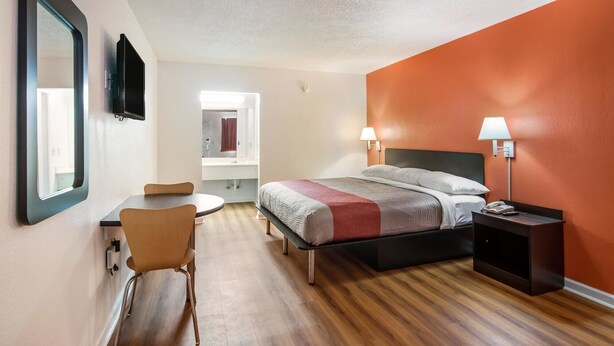 Quarto de hotel com cama, abajures, escrivaninha e cadeira.