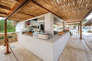 Disposição de buffet com estrutura de vidro, extintor de incêndio e carrinho com cestas de pão.