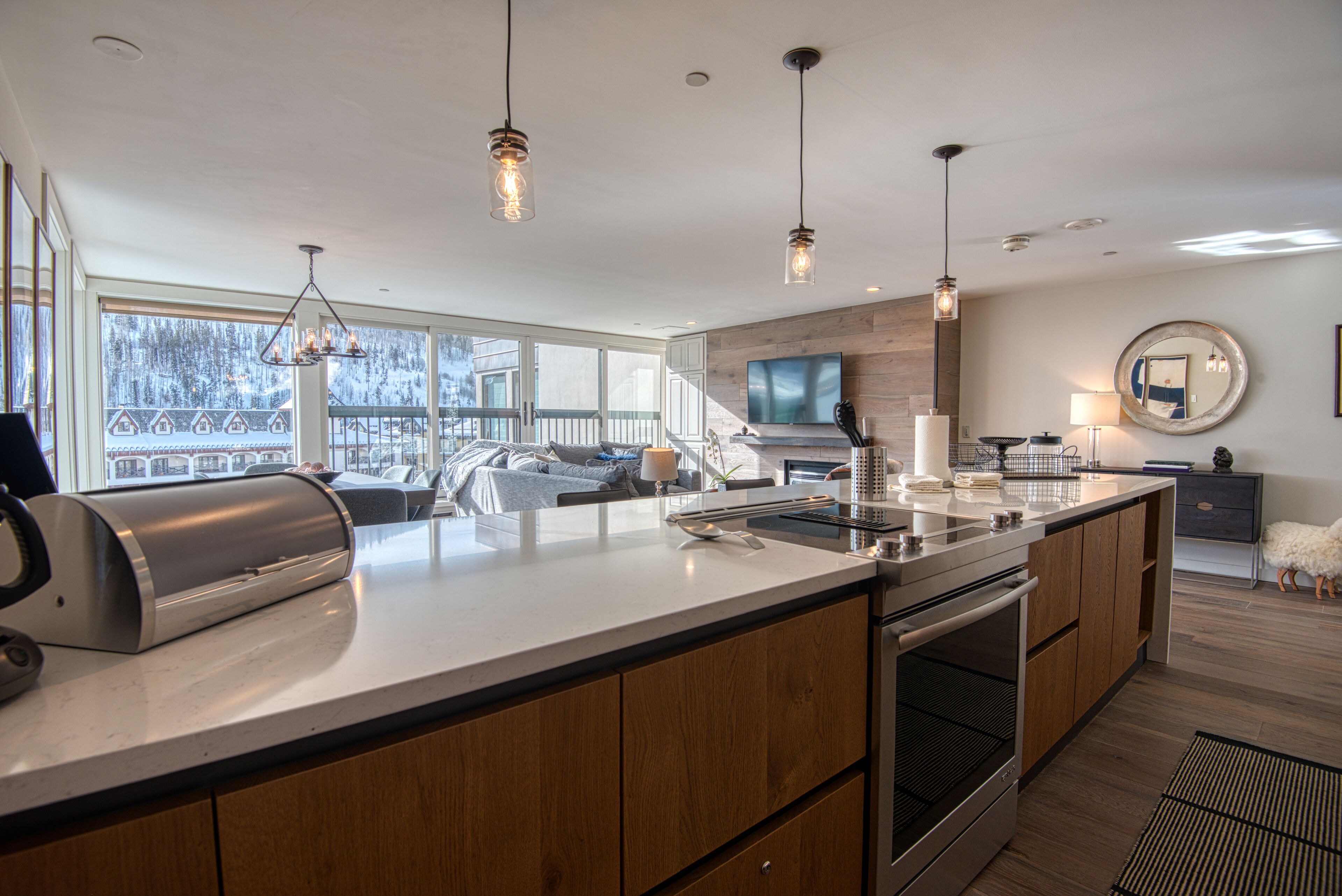 Cozinha moderna com uma ilha grande, eletrodomésticos de aço inoxidável e iluminação pendente.