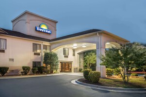 Um hotel Days Inn com entrada bem iluminada, área de estacionamento coberta e jardins bem cuidados.