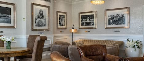 Uma área de estar luxuosa com poltronas de couro, uma mesa redonda e um sofá.