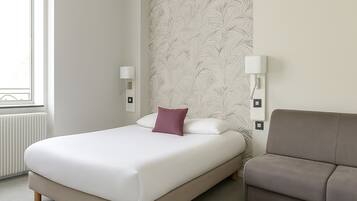 Quarto com cama, sofá, radiador e janela.