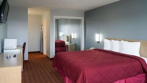 Quarto de hotel com cama, escrivaninha, cadeira, micro-ondas e telefone.