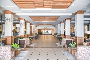 Um hall amplo com área central aberta, opções de assento e design moderno no teto.