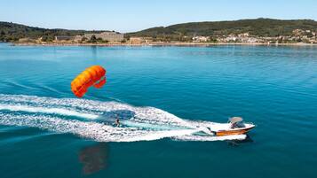 Passeio de parasail sobre a água, com um barco e um paraquedas.