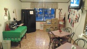 Uma área de refeições com uma mesa e cadeiras, uma geladeira e uma janela com vista.