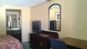 Quarto de hotel com uma cama, penteadeira, escrivaninha e espelho.