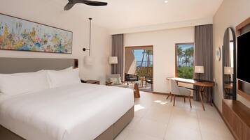 Quarto de hotel com cama grande, escrivaninha, cadeira, televisão e varanda com vista para o oceano.