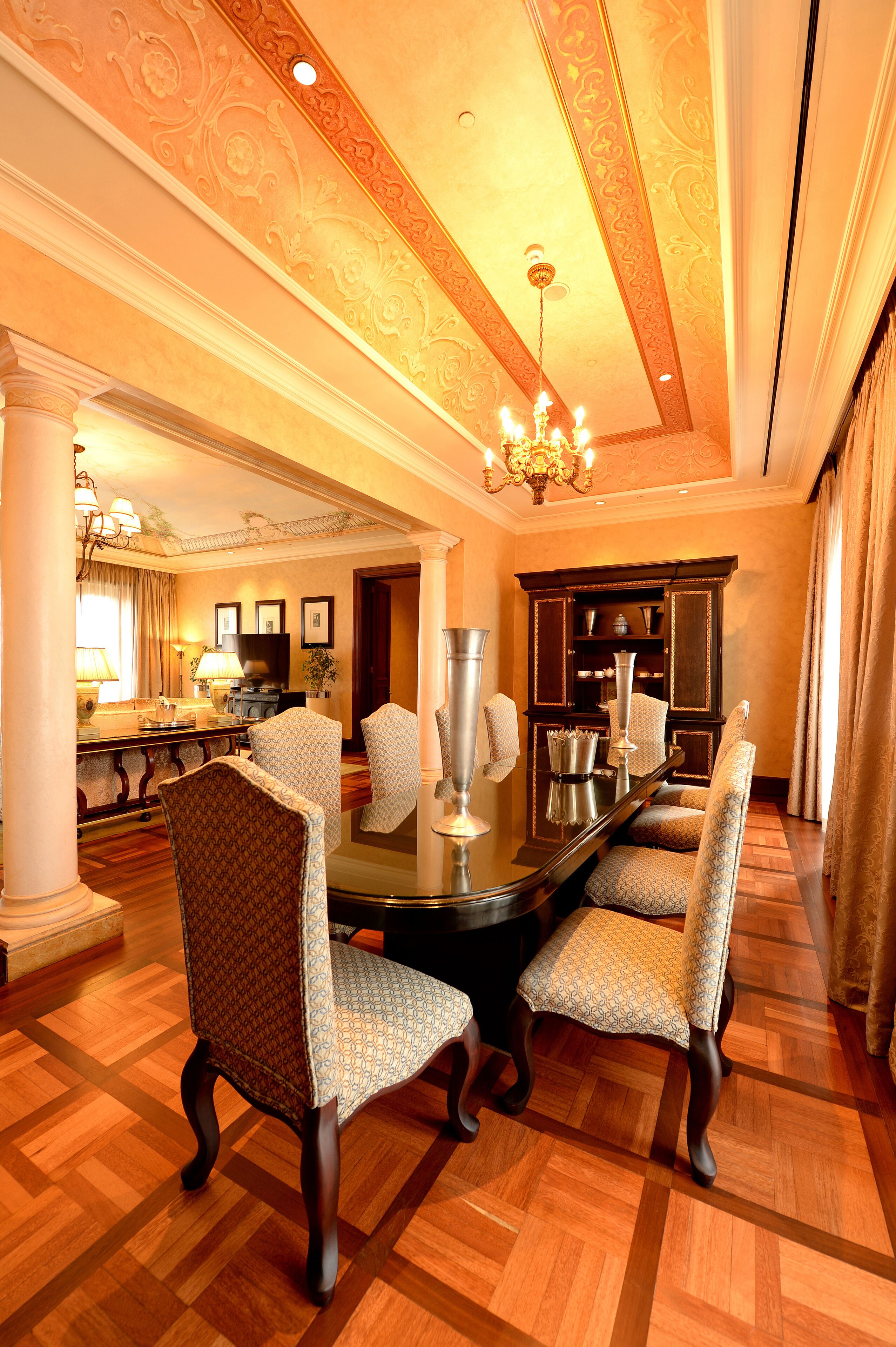 Uma sala de jantar com uma mesa comprida, quatro cadeiras estofadas e um candelabro.