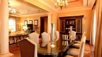 Uma sala de jantar com uma mesa comprida, quatro cadeiras estofadas e um candelabro.