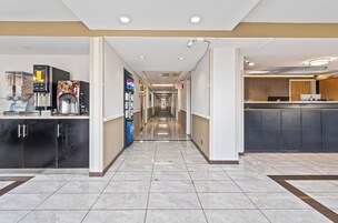 Corredor de hotel com uma estação de café, um refrigerador da Pepsi e um balcão de recepção.