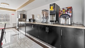 Cozinha moderna com bancada preta, eletrodomésticos de aço inoxidável e uma janela com persianas.