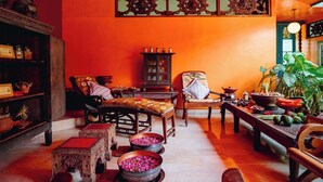 Quarto tradicional com parede vermelha, mobiliário de madeira e um armário com objetos decorativos.