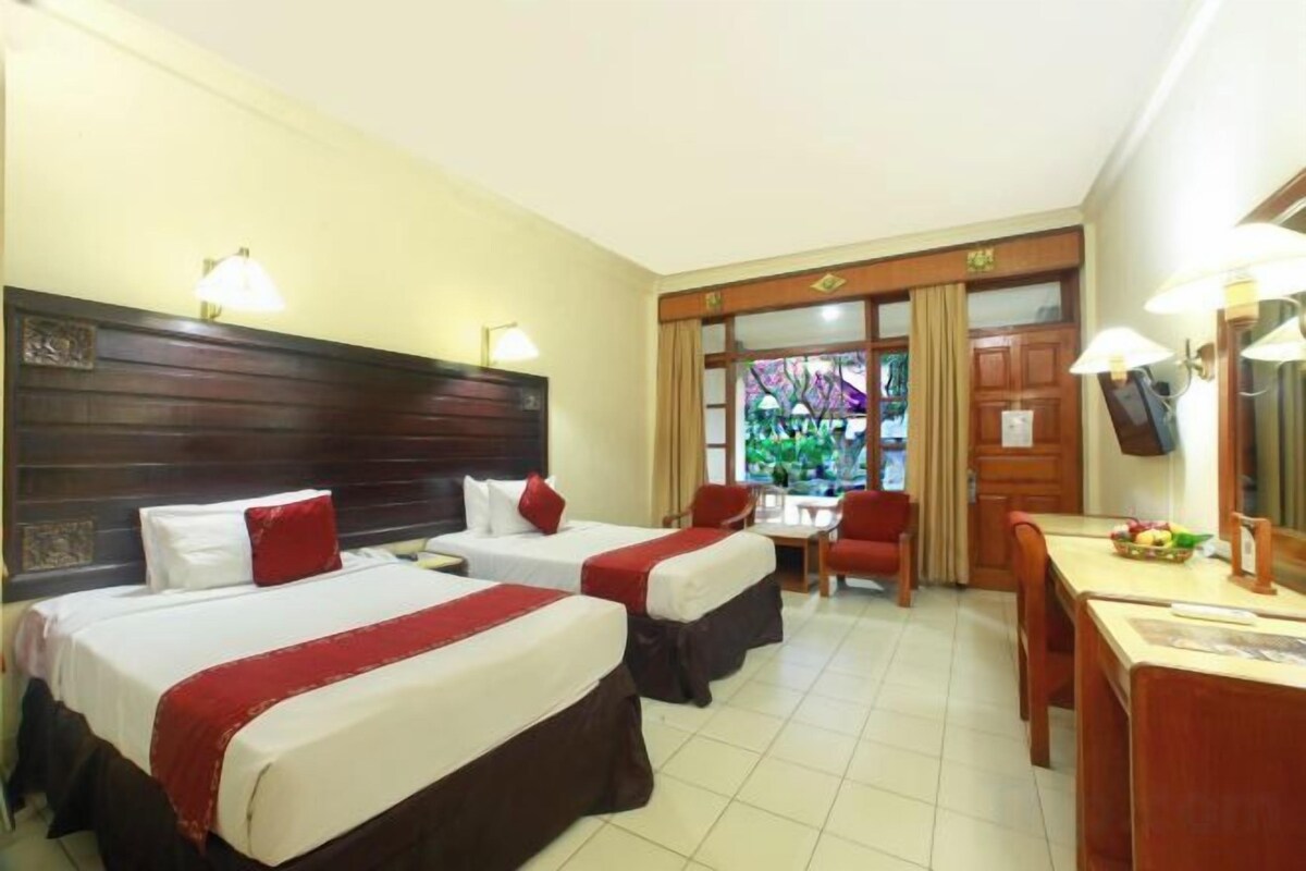 Quarto de hotel com duas camas, uma escrivaninha, uma cadeira e uma televisão.