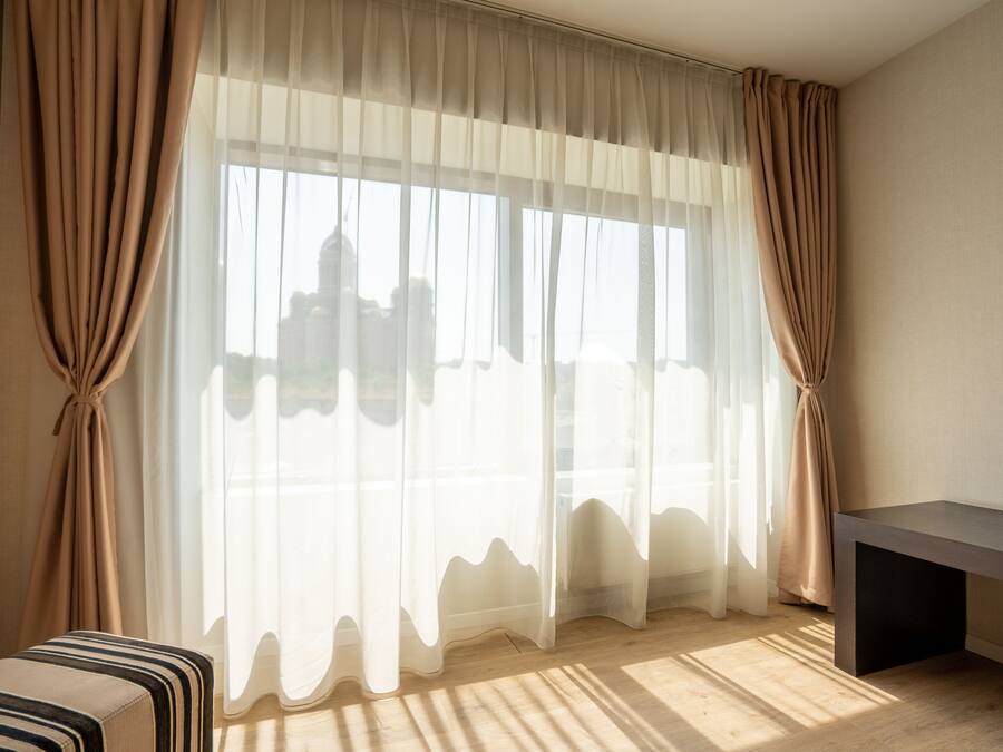 Um quarto com grandes janelas, um banco e uma lareira.