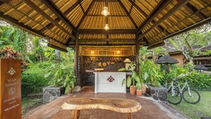 Uma área de recepção com um balcão de madeira, parede de pedra e uma placa com a inscrição 'Villa Semana'.