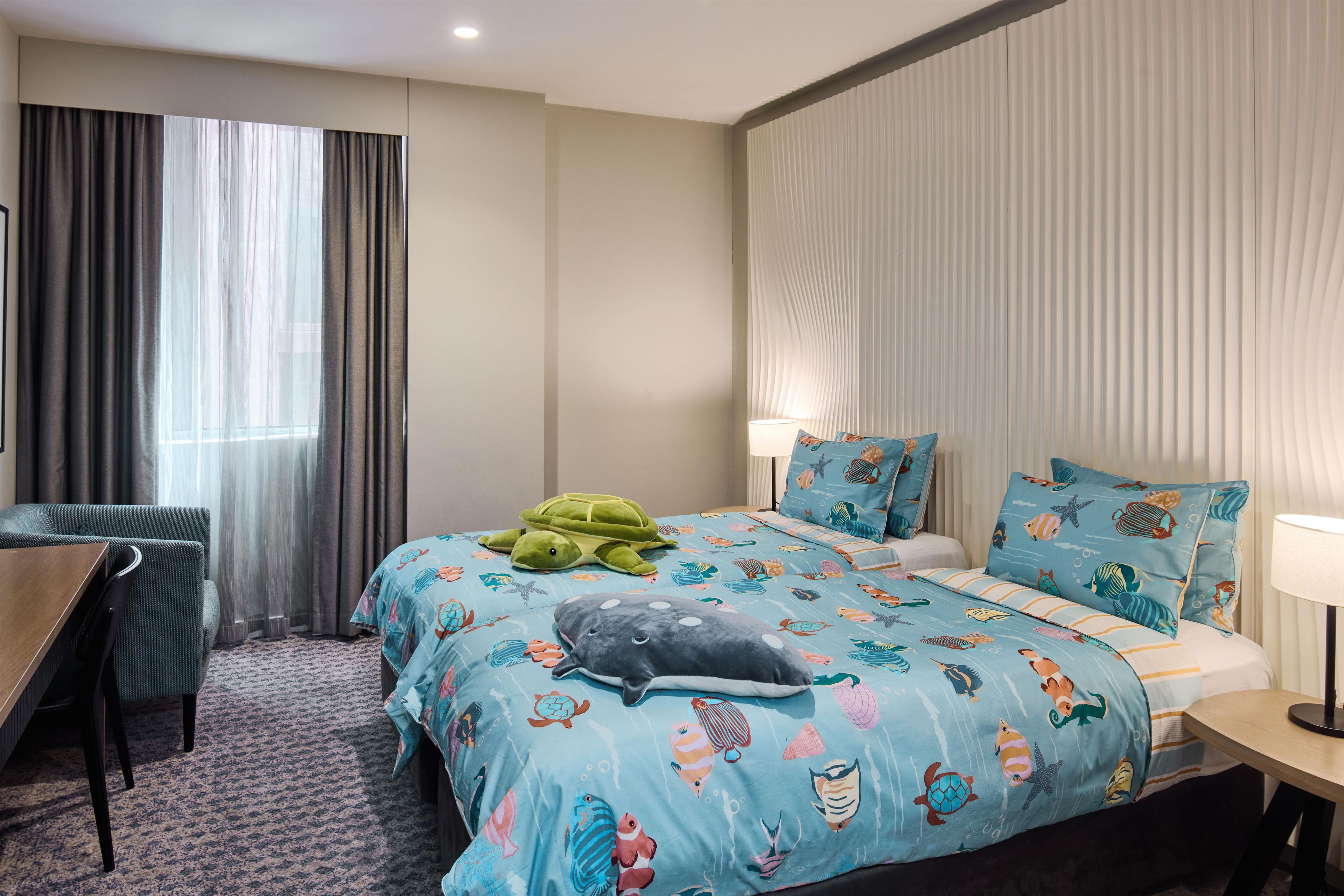 Quarto de hotel com cama, escrivaninha e cadeira.