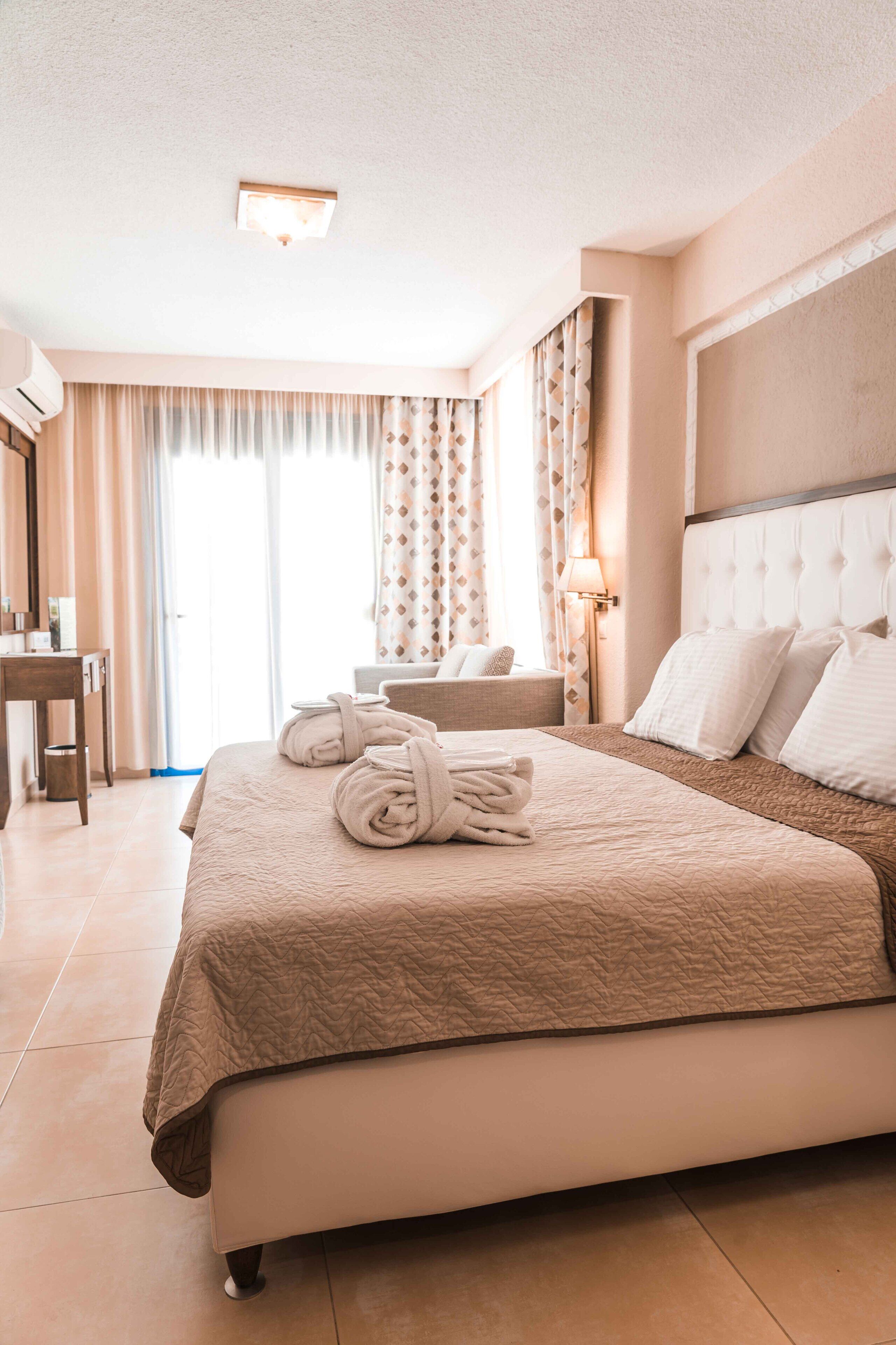 Quarto de hotel com uma cama grande, uma escrivaninha e uma cadeira.