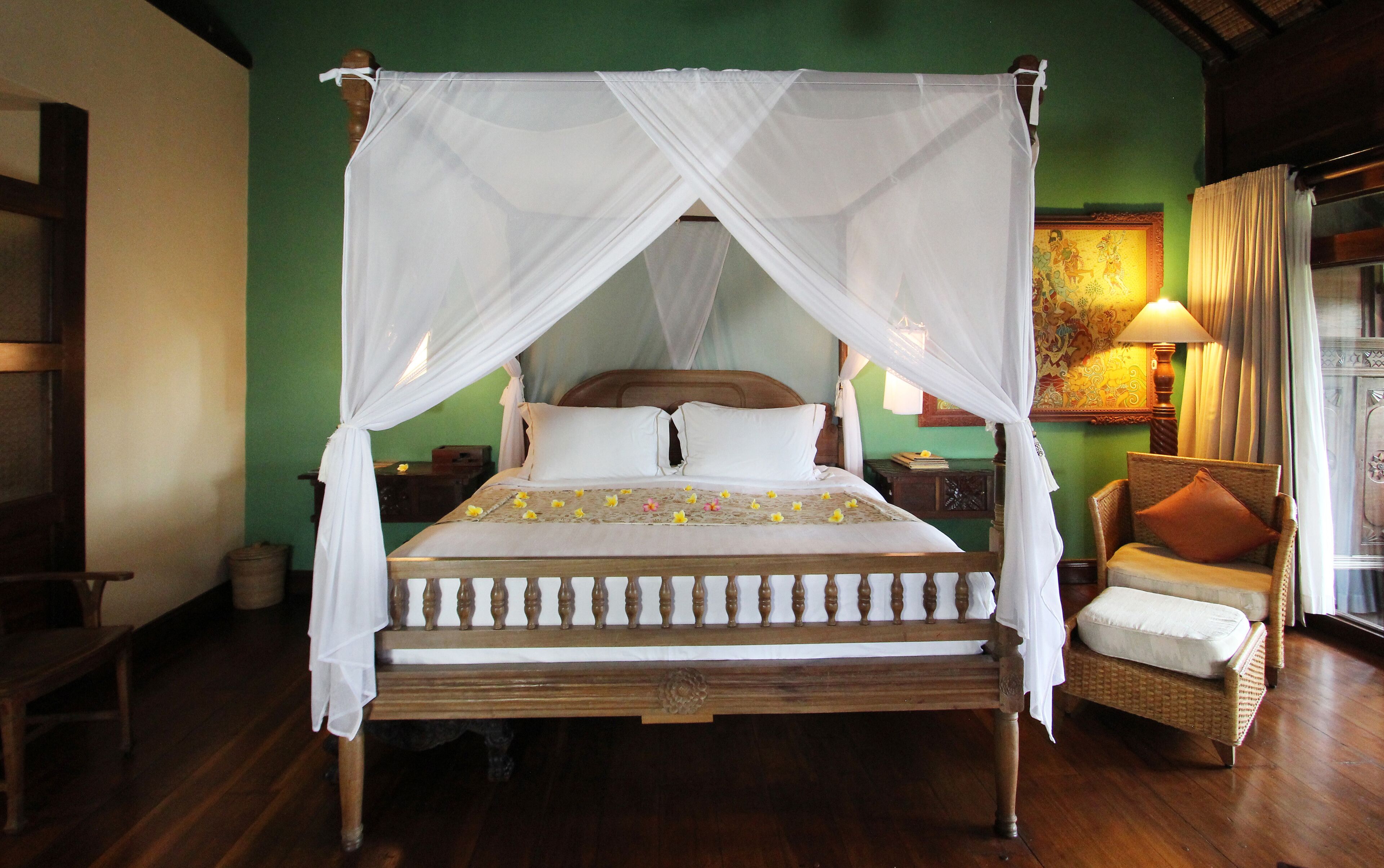 Uma cama de dossel com estrutura de madeira, cabeceira de madeira e edredom floral.