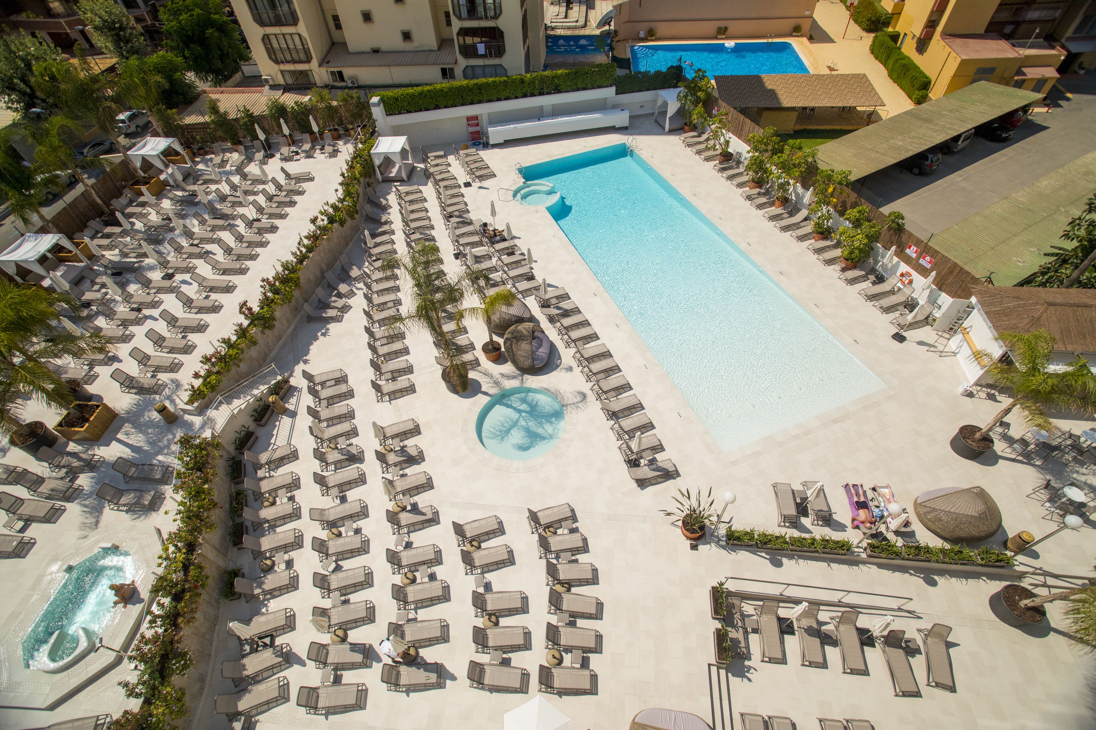Vista aérea de um resort com várias piscinas, espreguiçadeiras e paisagismo bem cuidado.