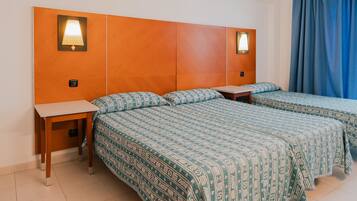 Quarto de hotel com duas camas, cada uma com roupa de cama estampada, mesinhas de cabeceira de madeira e luminárias fixadas na parede.