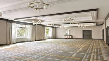 Um quarto amplo, com grandes janelas, um tapete estampado e vários lustres.