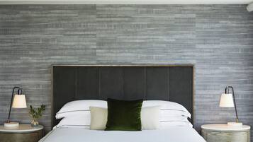 Um quarto moderno com uma cama grande, duas mesas de cabeceira e uma parede texturizada.