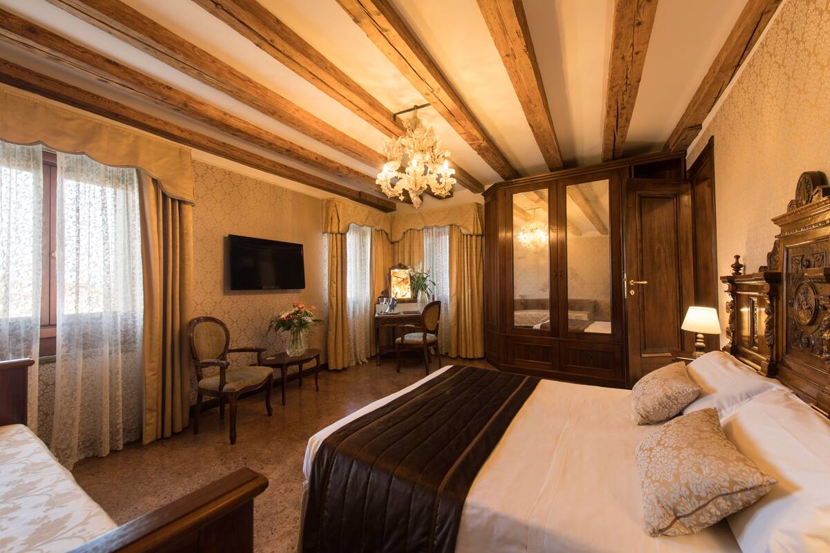 Quarto de hotel com uma cama grande, uma escrivaninha, uma cadeira e um guarda-roupa.