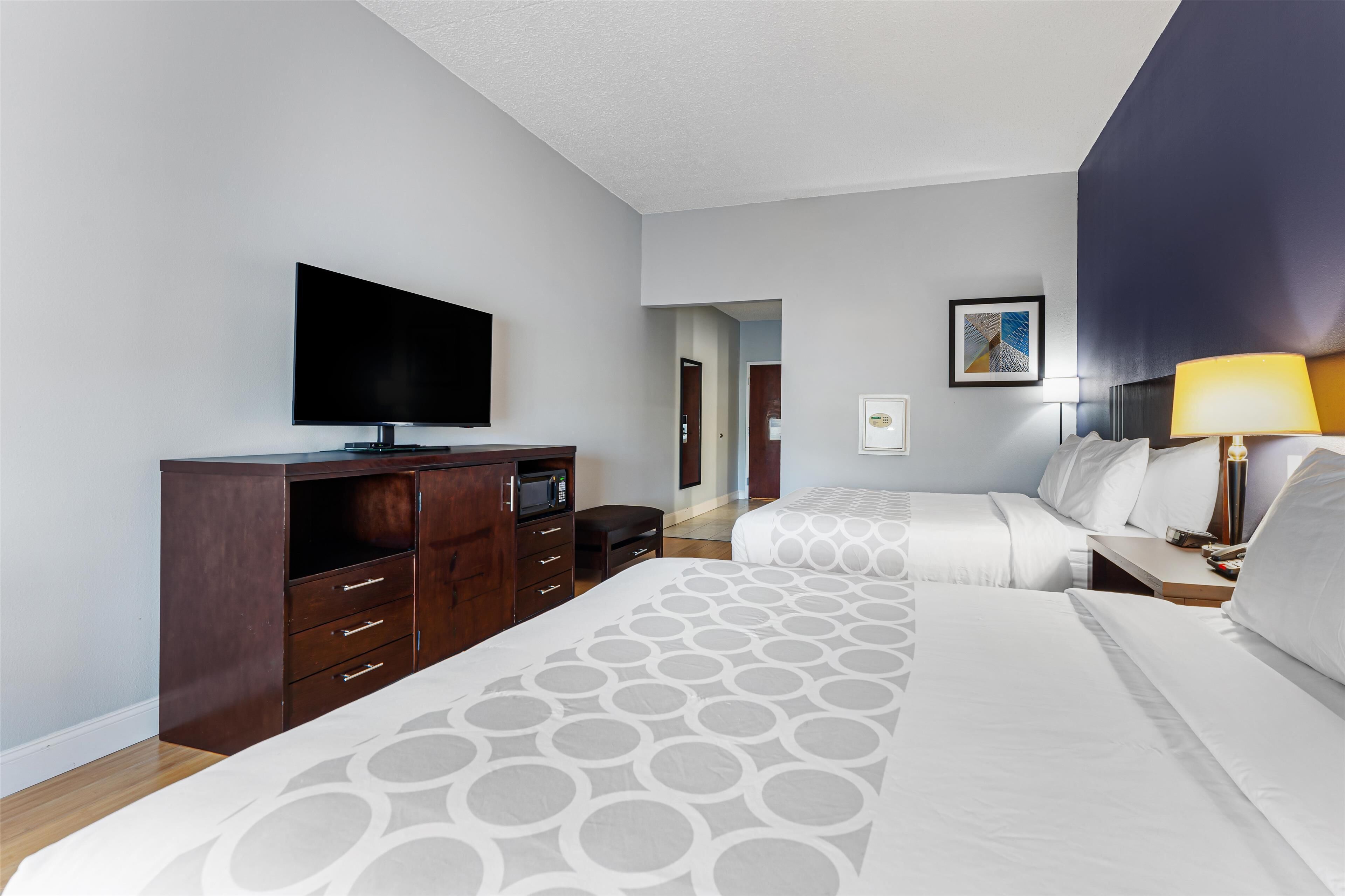 Quarto de hotel com uma cama grande, televisão, escrivaninha e abajur.