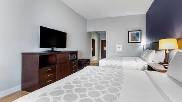 Quarto de hotel com uma cama grande, televisão, escrivaninha e abajur.