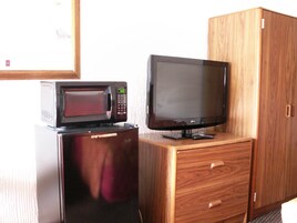 Uma cozinha compacta com micro-ondas e uma televisão de tela plana sobre um armário de madeira.