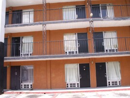 Um edifício com vários andares, varandas, portas pretas e cortinas brancas.